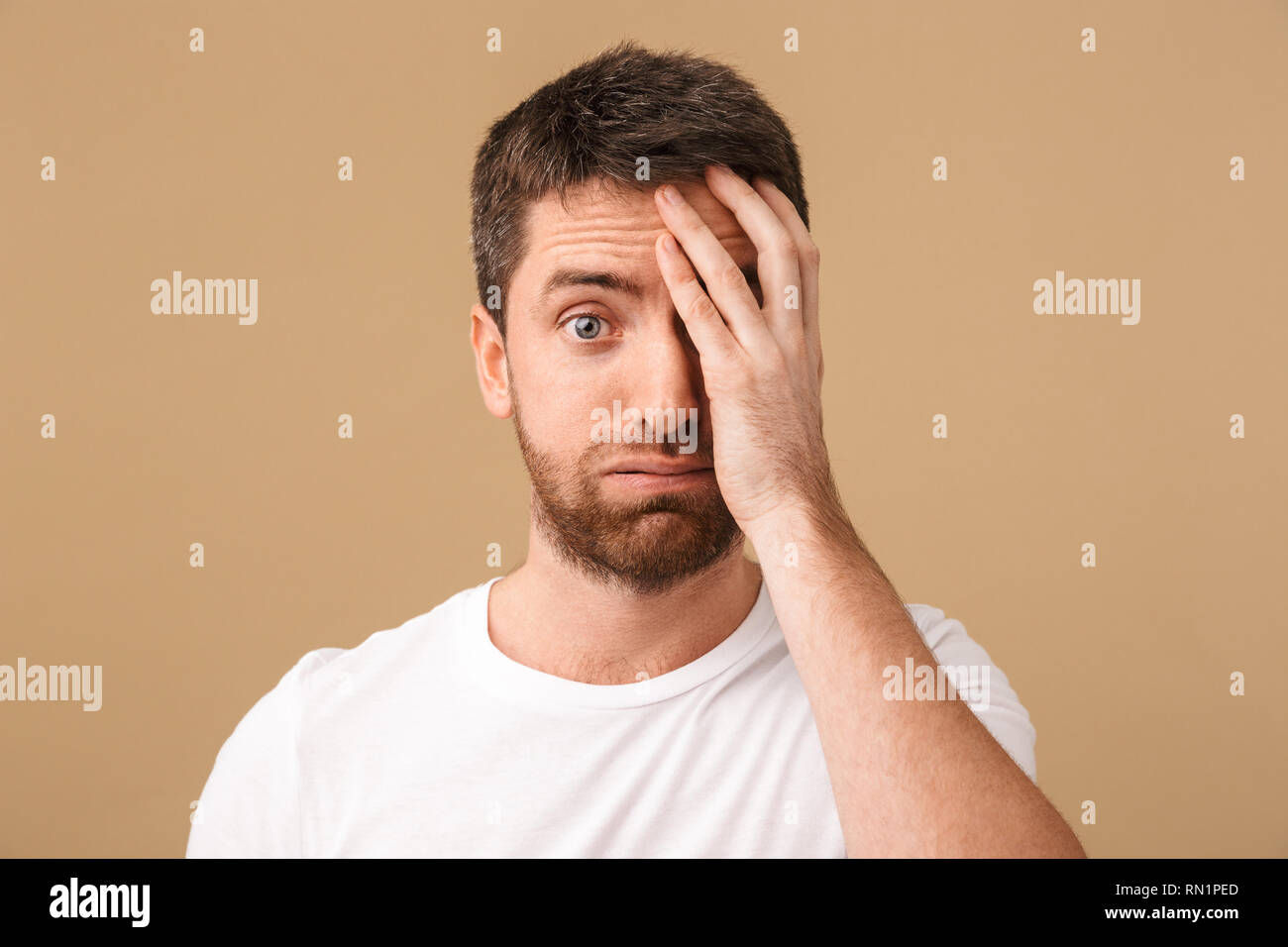 Portrait of a confused young man casually dressed standing isolated ...