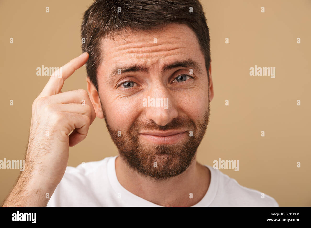 Portrait of a confused young man casually dressed standing isolated ...