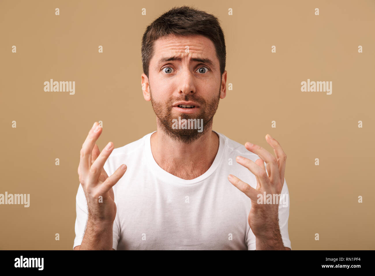 Portrait of a shocked young man casually dressed standing isolated over ...