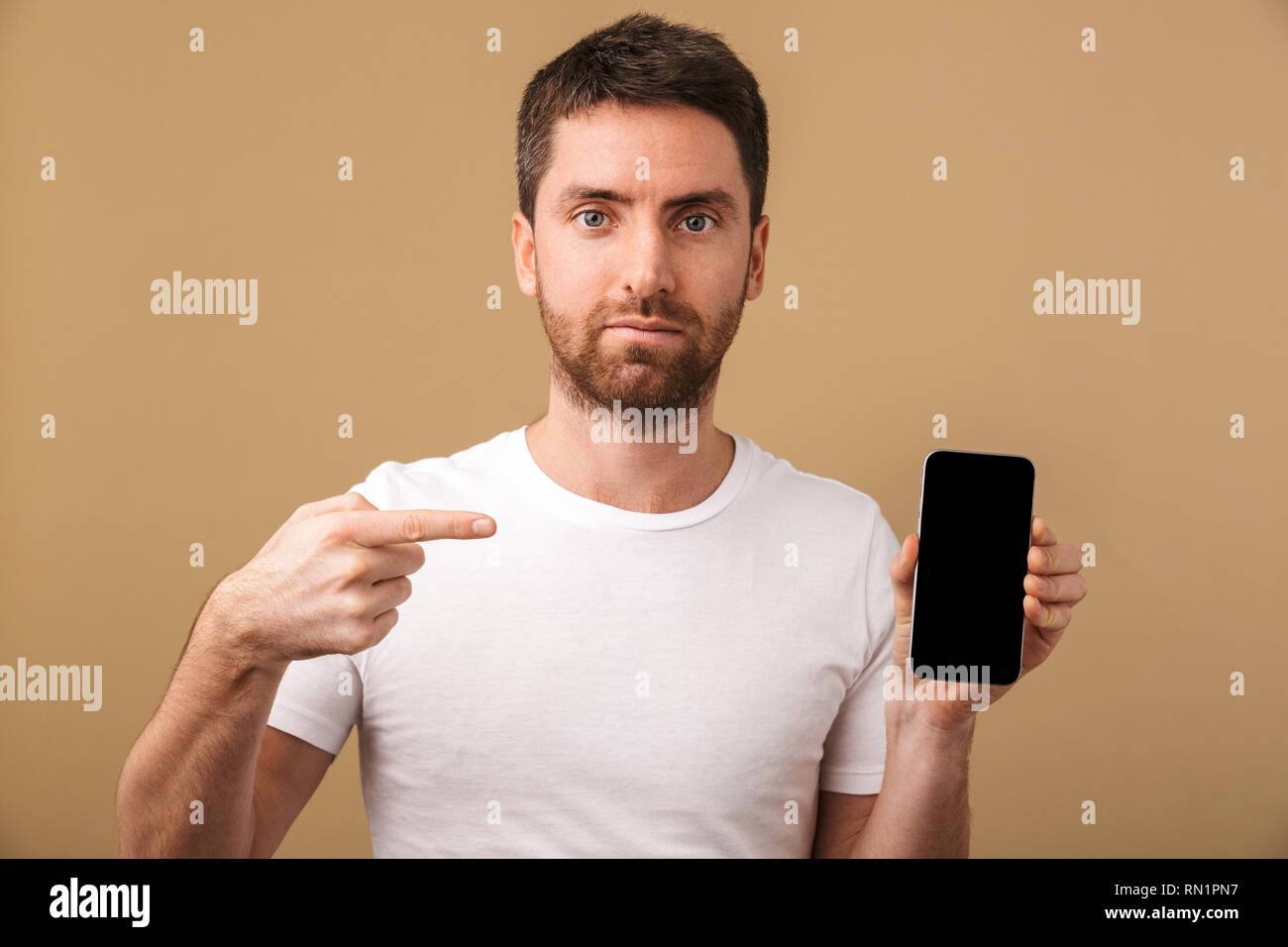 Confused young casual man showing blank screen mobile phone isolated ...
