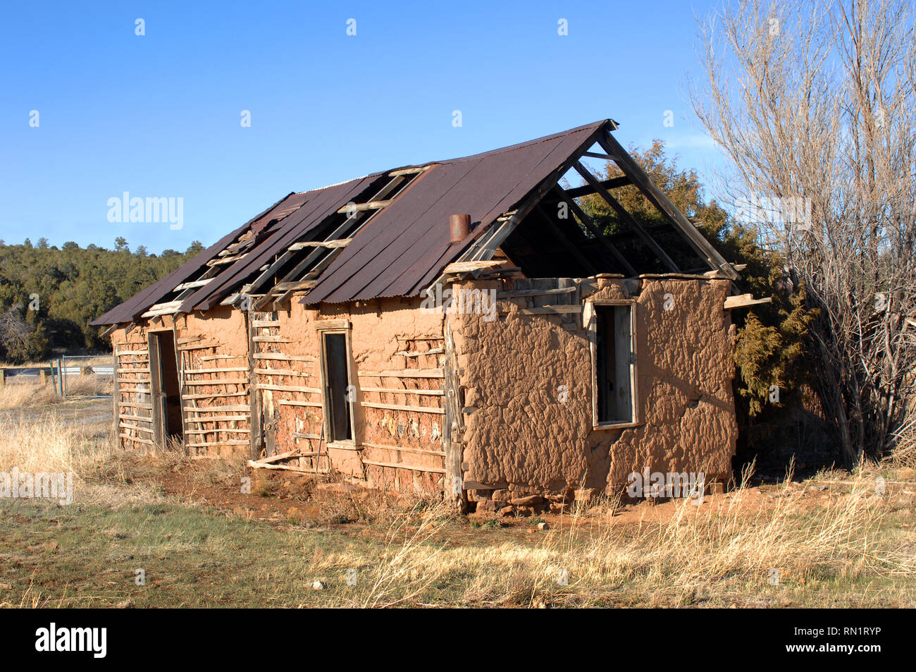 Old adobe building is crumbling into disrepair. Long abandoned, wooden supports show through the ...
