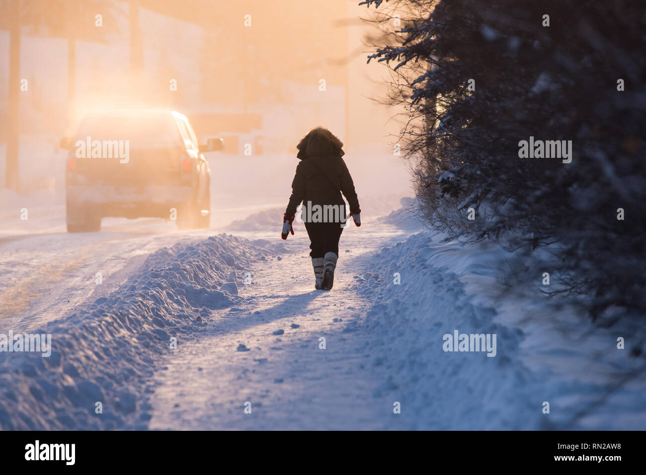 A woman dressed for extreme cold walks through Old Town at sunset in ...