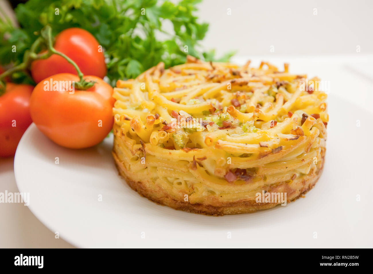 Delicious italian macaroni pasta cake with tomatoes and bacon on white ...