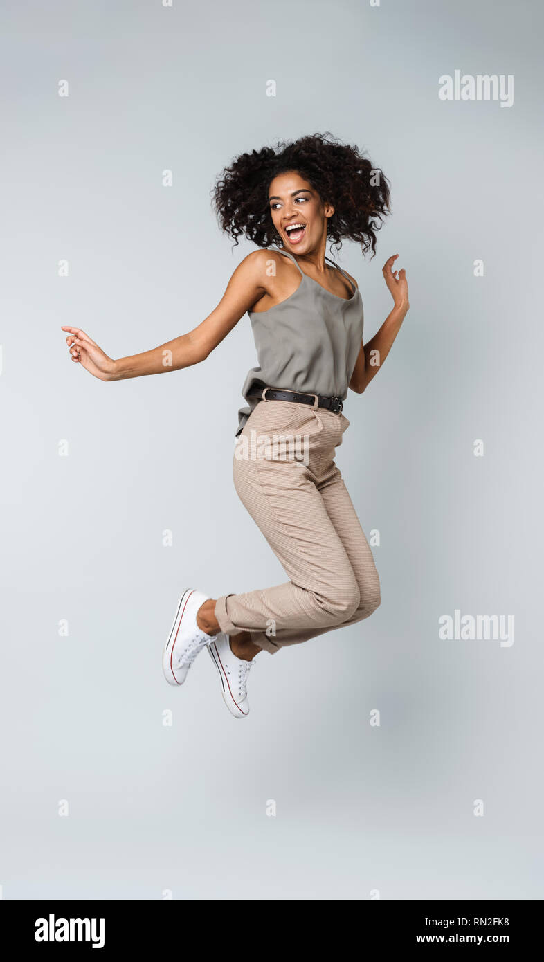Full length of a happy young african woman casually dressed jumping ...