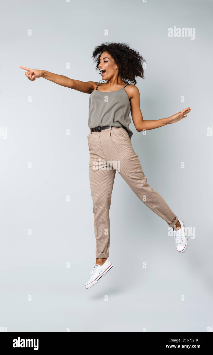 Full length of a happy young african woman casually dressed jumping ...