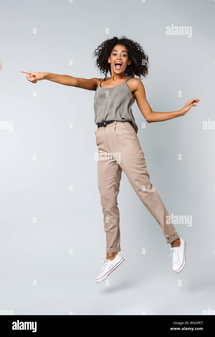 Full length of a happy young african woman casually dressed jumping ...
