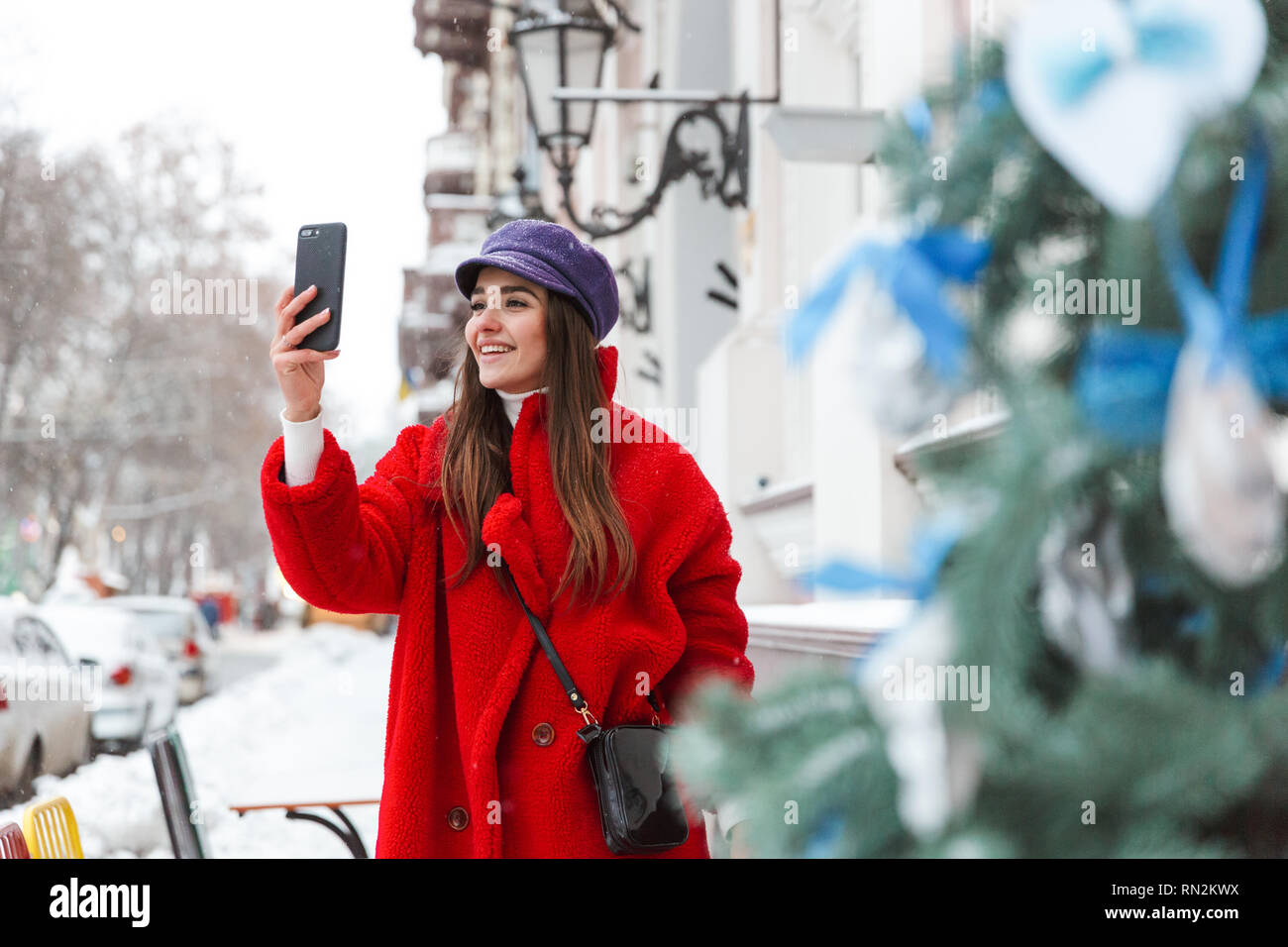 Image of a pretty young woman outdoors walking at snow winter street ...