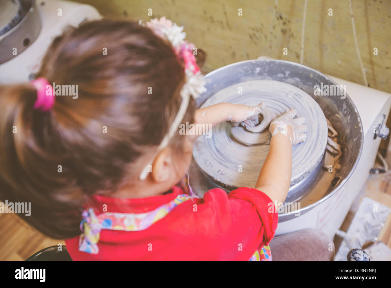 Top view of little girl making clay on pottery wheel at workshop Stock ...