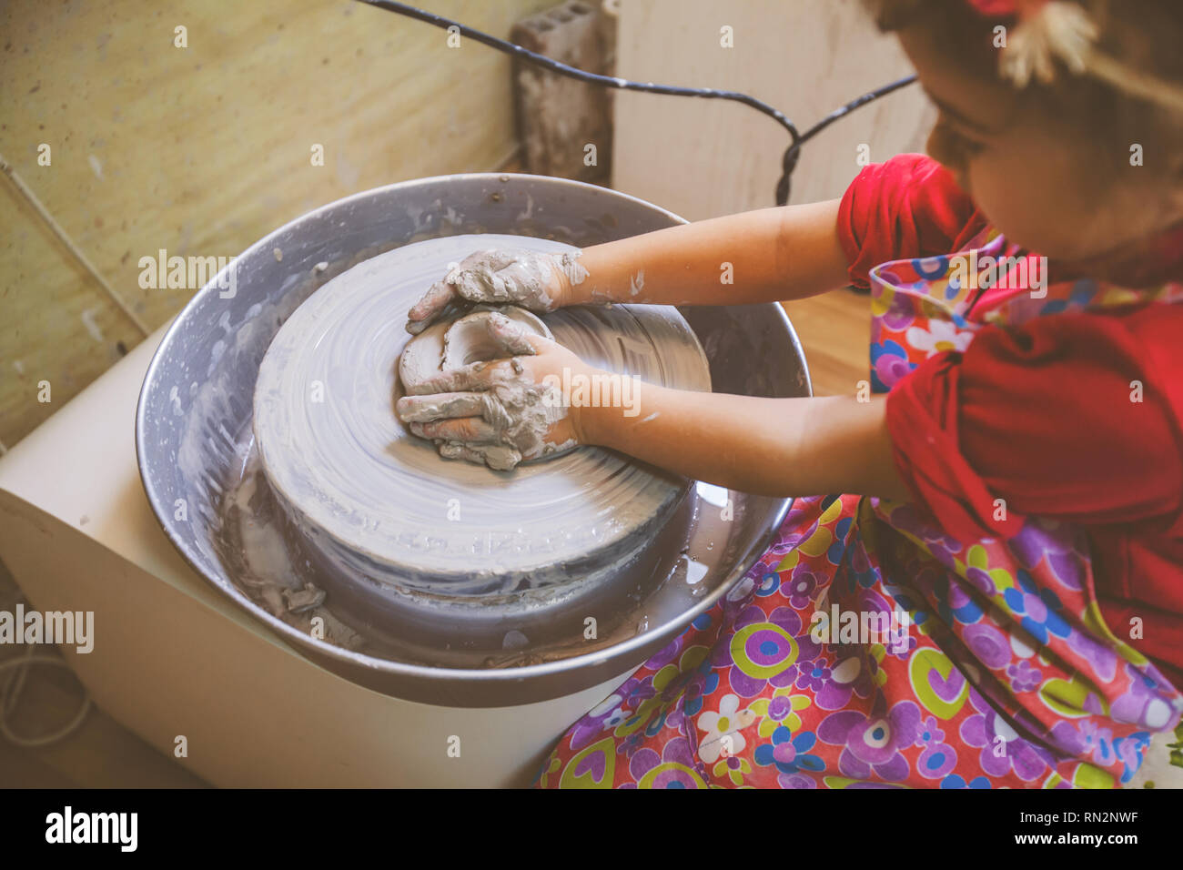 Top view of little girl making clay on pottery wheel at workshop Stock ...