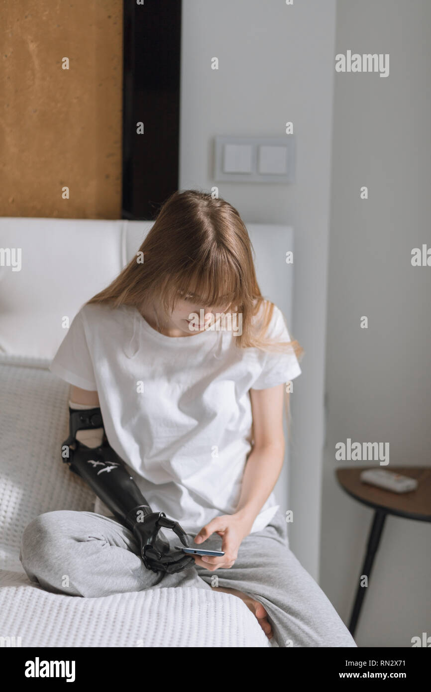 disabled young woman with prosthetic arm using her smartphone. new ...