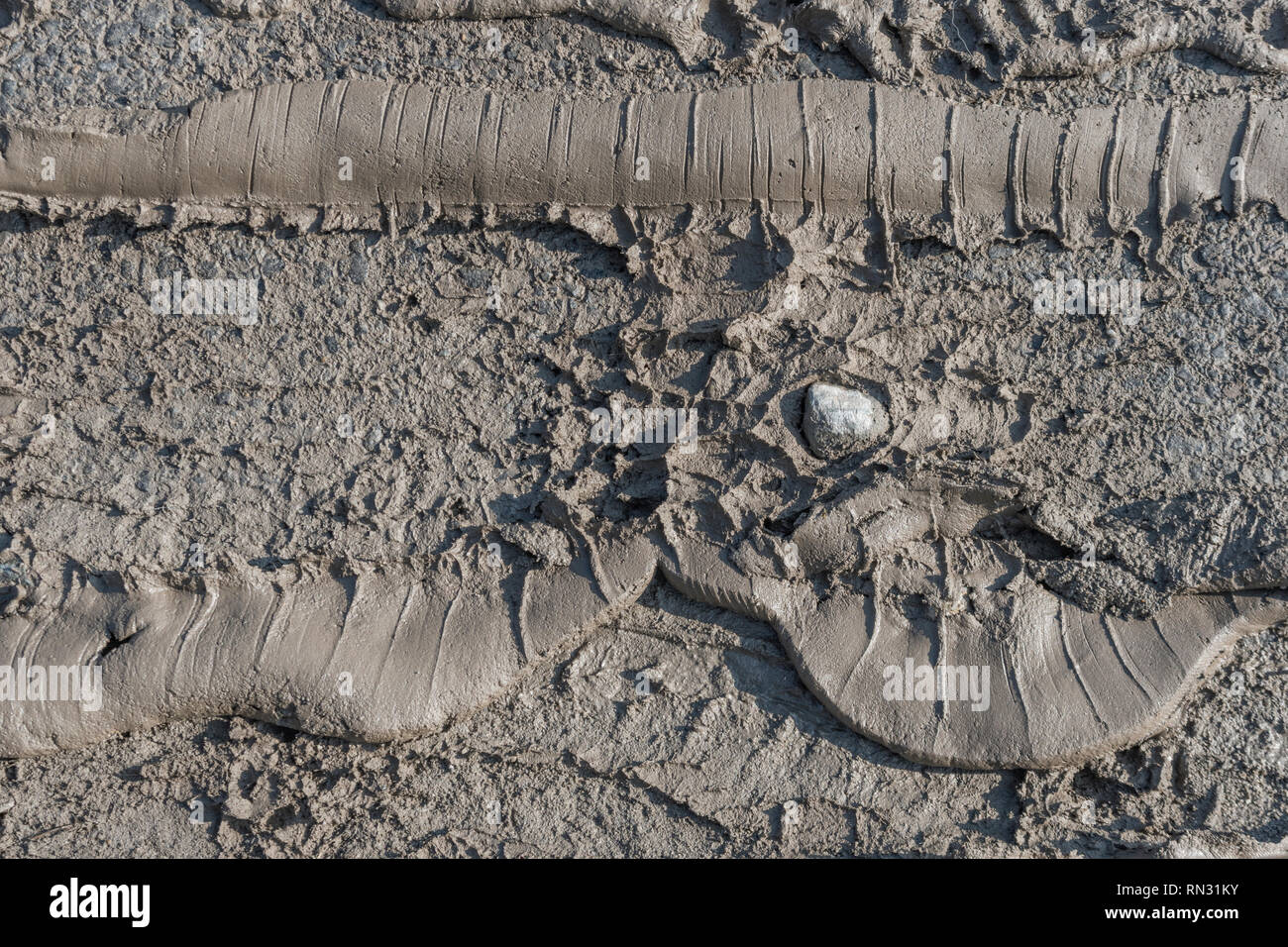 Tyre tracks in slippery wet mud on road. Metaphor stick in the mud ...