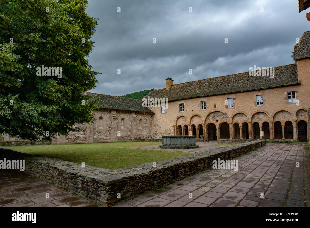 Conques, France - June 2015: Fountain and arcade in the interior ...