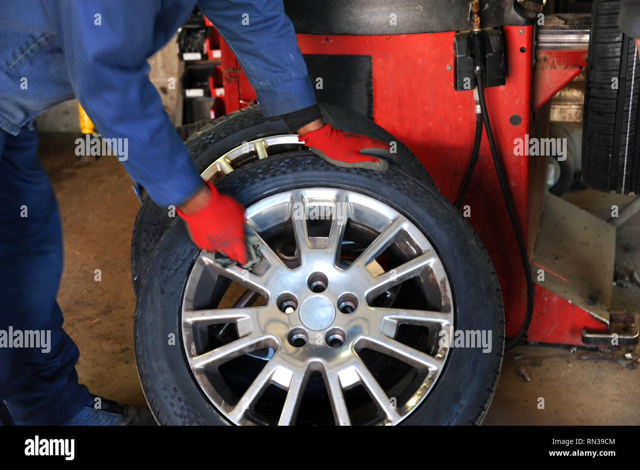 Worker at a tire store, rubs and polishes a chrome rim on a wheel. He ...