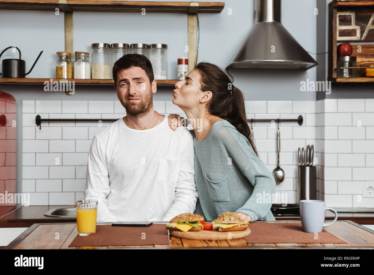 Young couple sitting at the kitchen during breakfast at home, woman ...