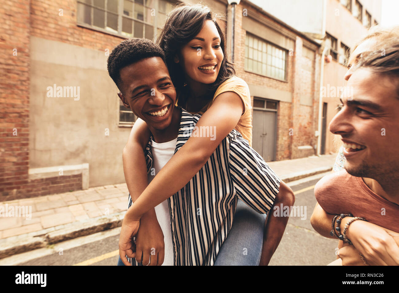 Two men giving piggyback ride to their girlfriends outdoors. Multi ...
