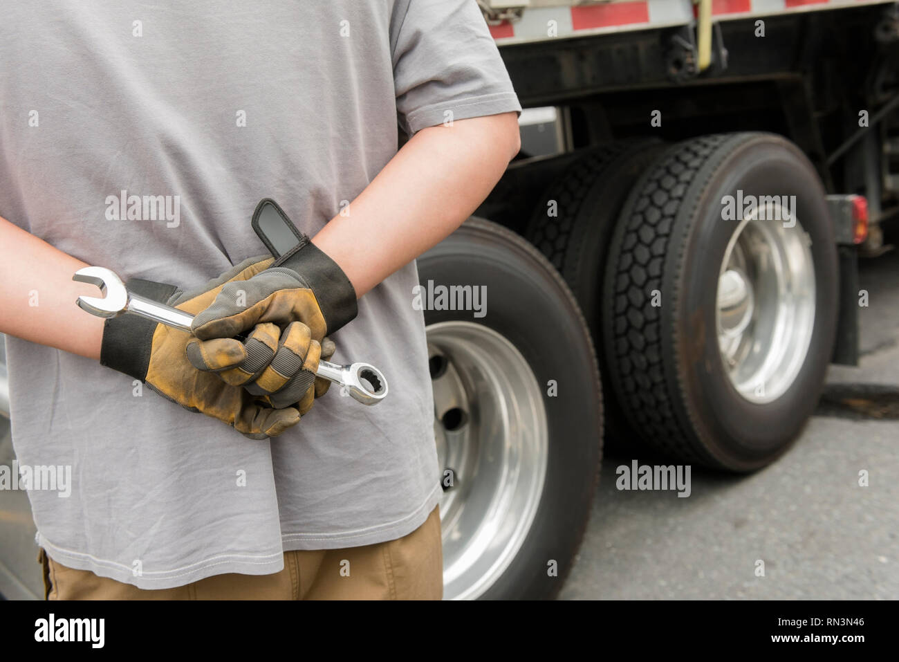 Man's hands behind his back holding wrench Stock Photo - Alamy