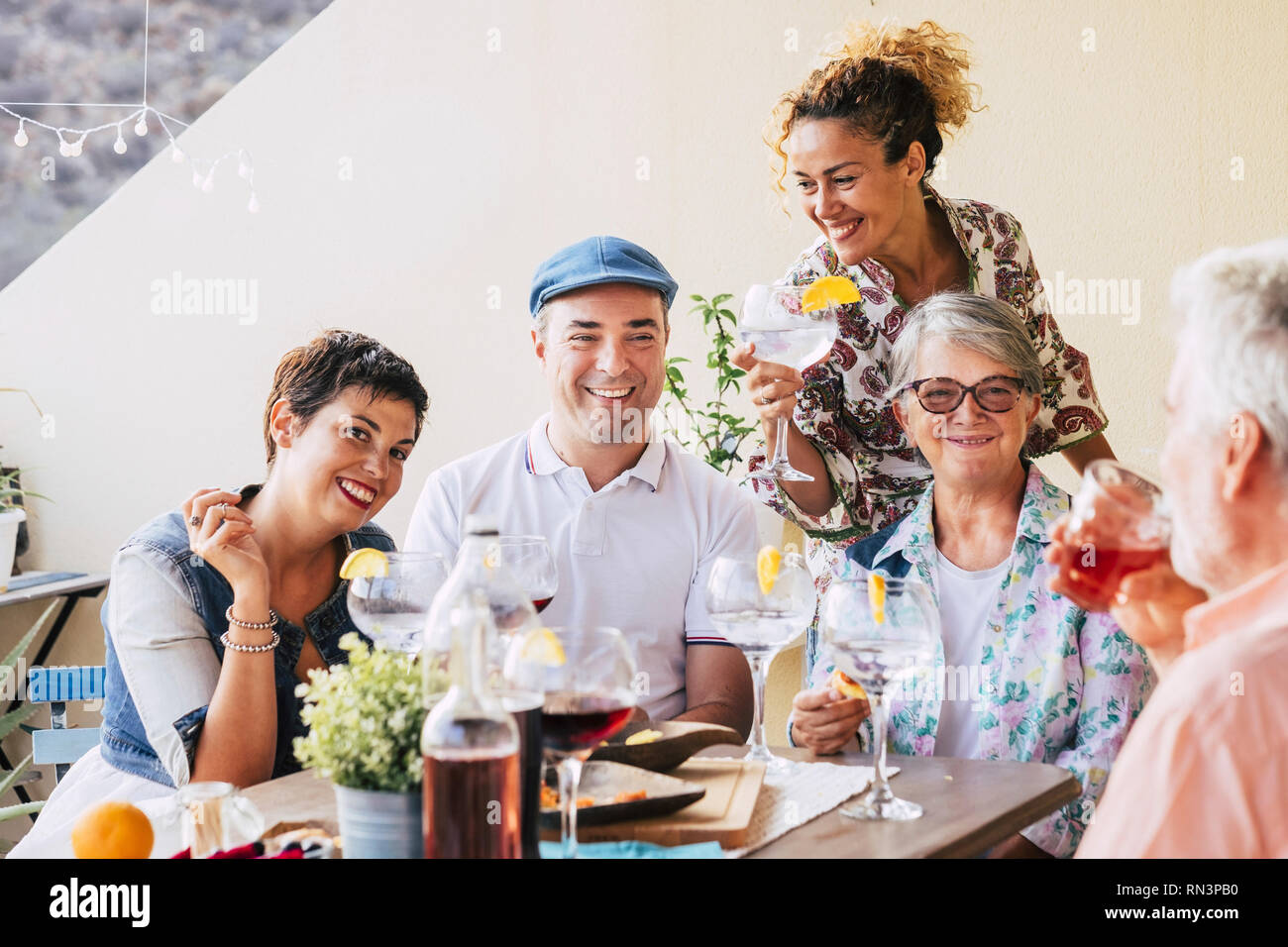 Family and friends at lunch all together at home in the terrace ...