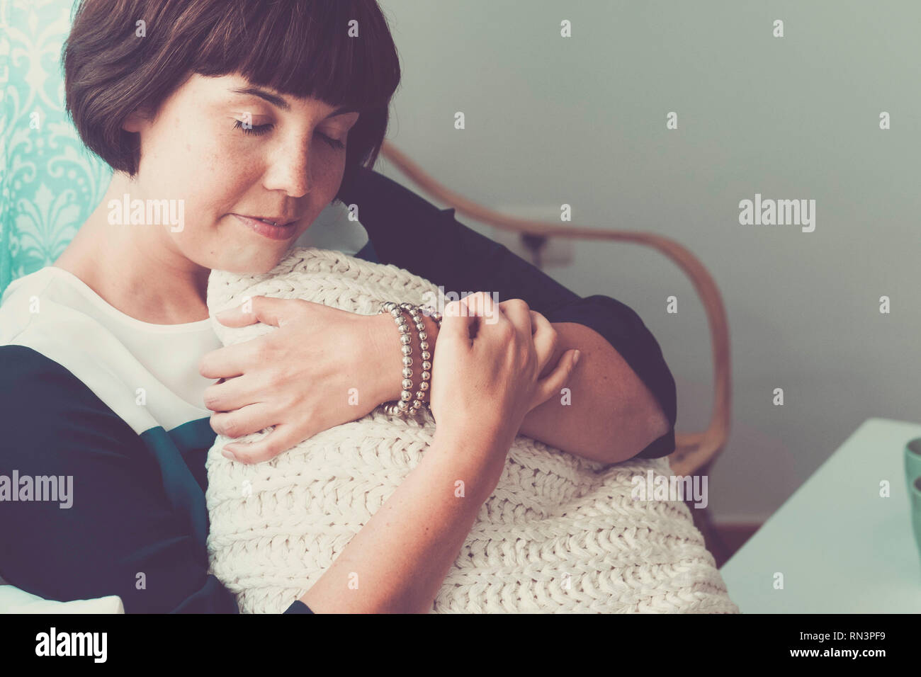 Sweet young woman hug with love and protection a white cover at home ...