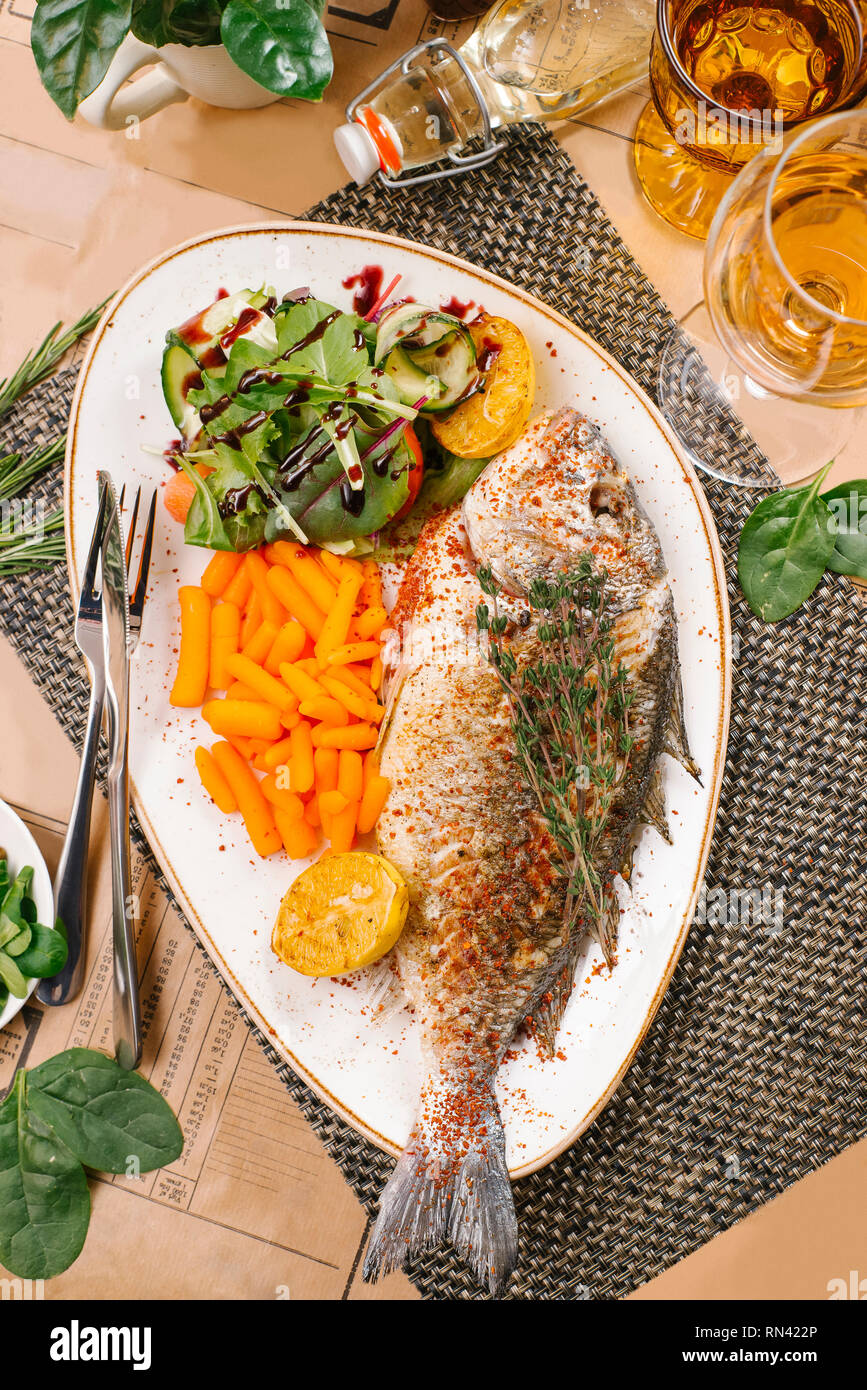 Fried fish with baby carrots and salad Stock Photo - Alamy