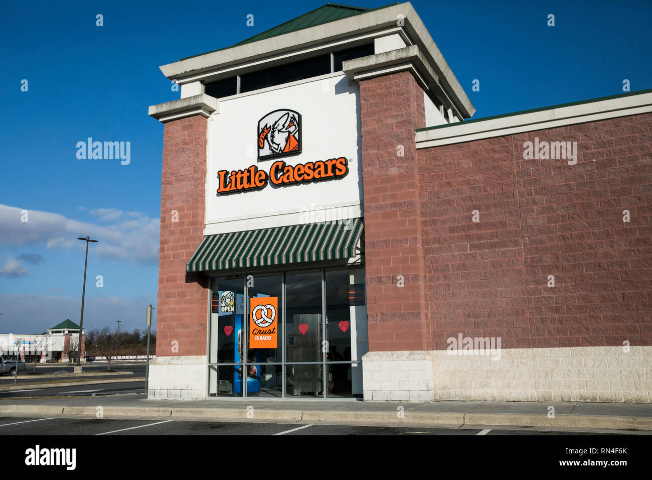 A logo sign outside of a Little Caesars restaurant location in ...