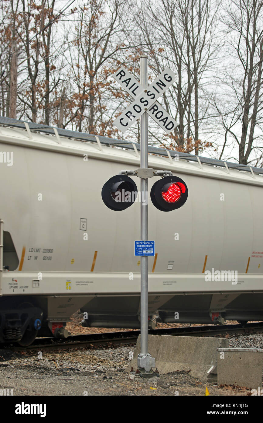 A Railroad Crossing warning sign with flashing lights and a train car ...