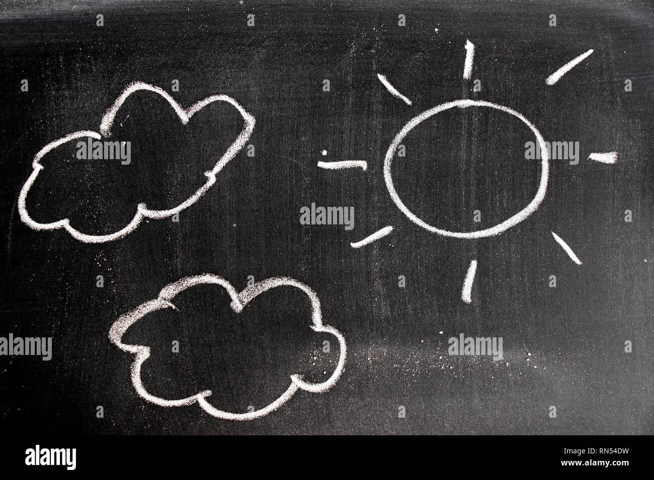Hand drawing of white chalk in sun and cloud shape on black board ...