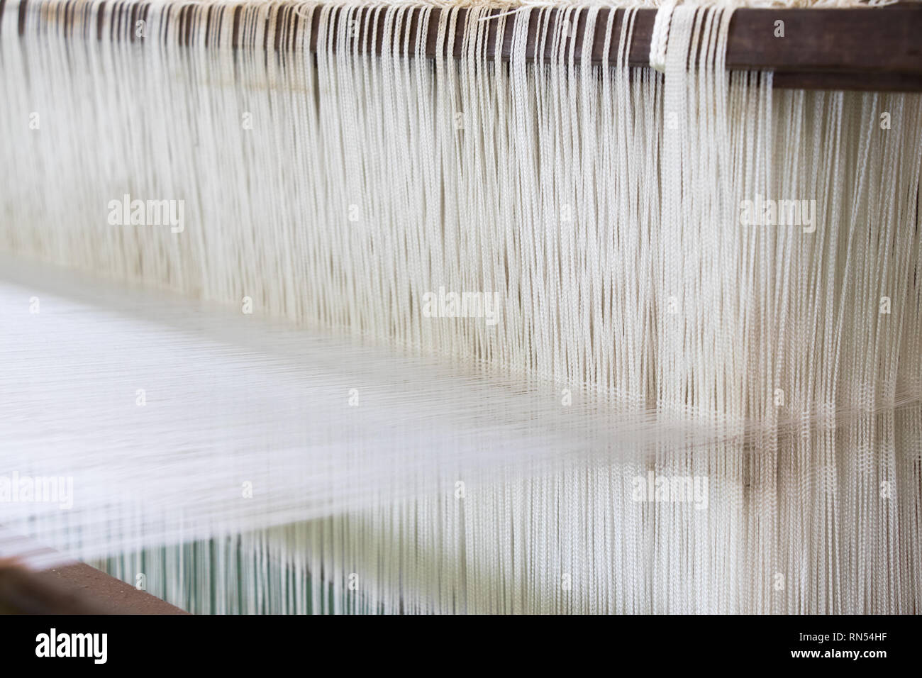 Closed up of loom with white thread background Stock Photo - Alamy