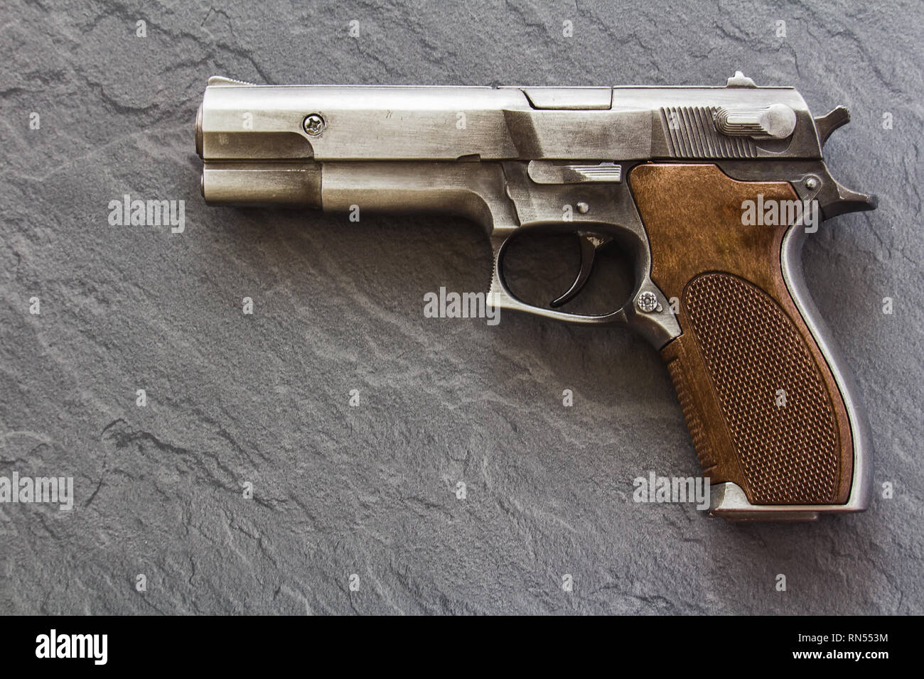 Handgun pistol on dark marble background from side Stock Photo - Alamy