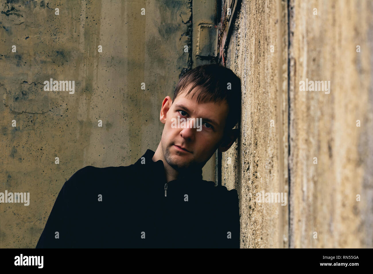 Portrait of young man with head on wall Stock Photo - Alamy