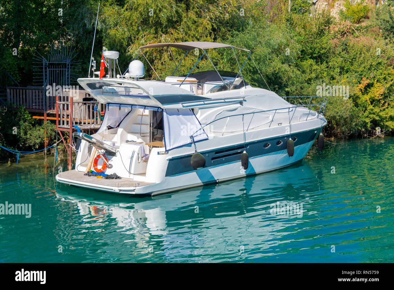 A small speedboat moored at the pier along the coast against a blue sky ...