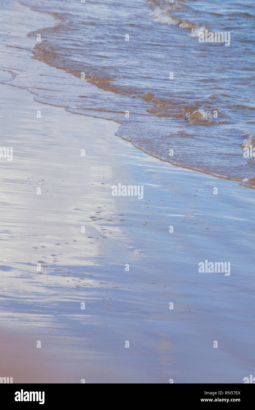 Clam waves breaking on sandy beach Stock Photo - Alamy