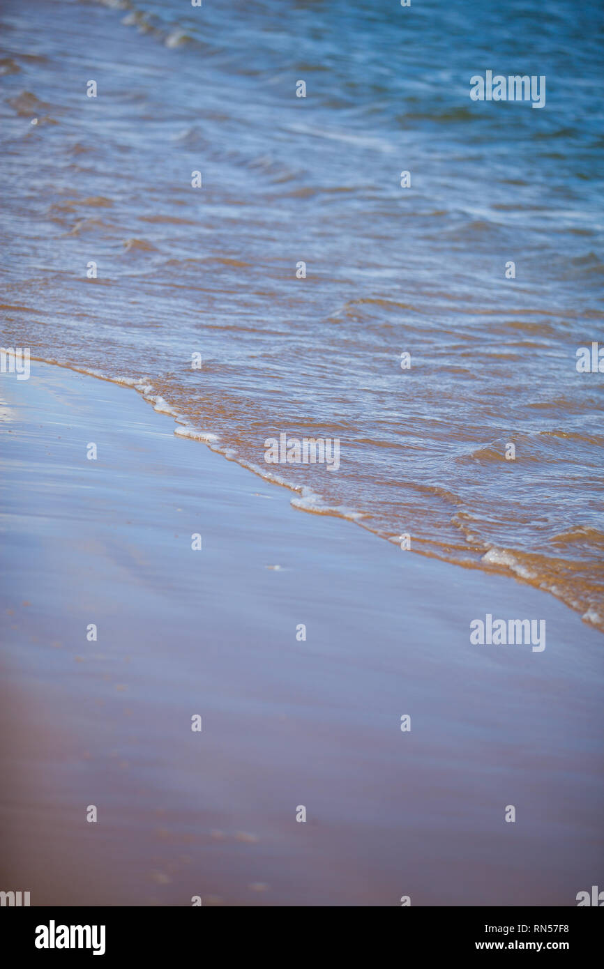 Clam waves breaking on sandy beach Stock Photo - Alamy