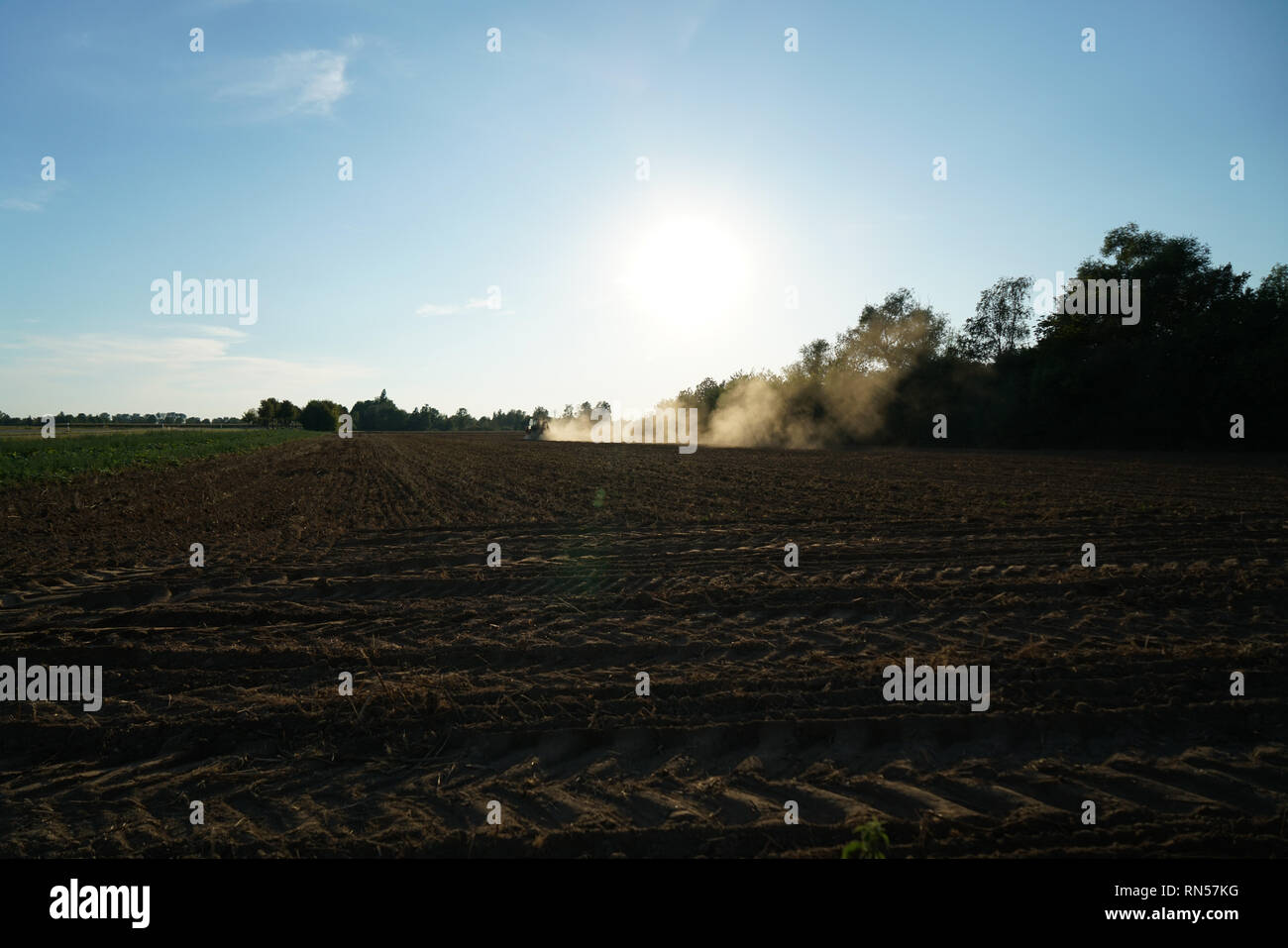 Just before sunset, a farmer was still working on a dusty field Stock ...