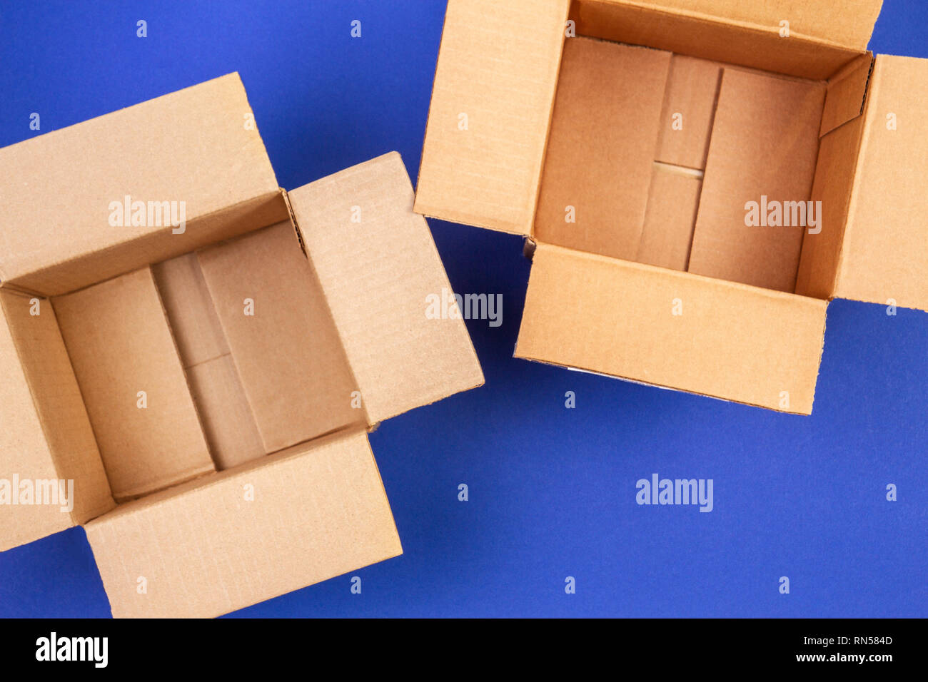 Two empty open cardboard boxes on blue background Stock Photo - Alamy