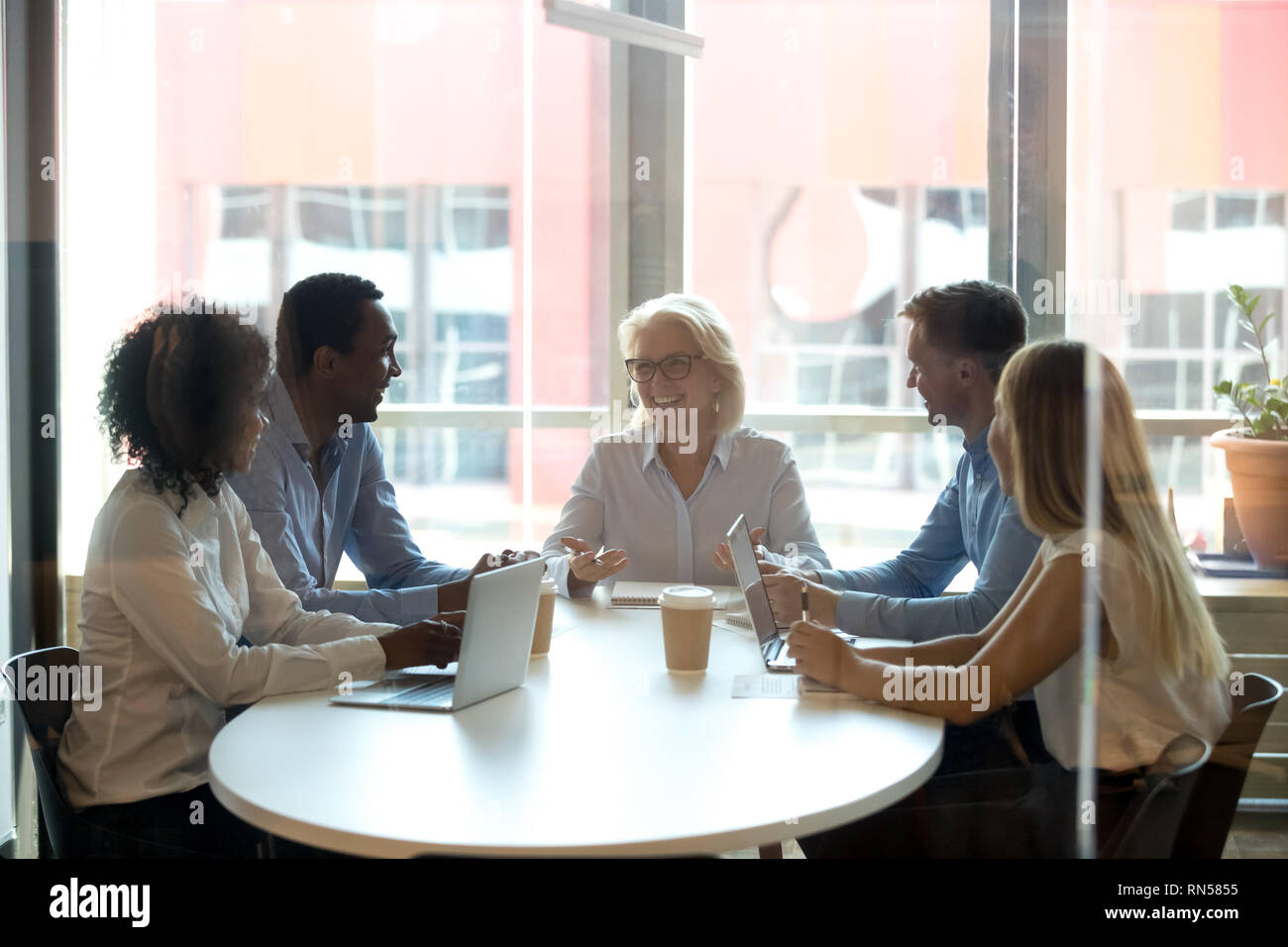 Five diverse businesspeople sitting in boardroom and negotiating Stock ...