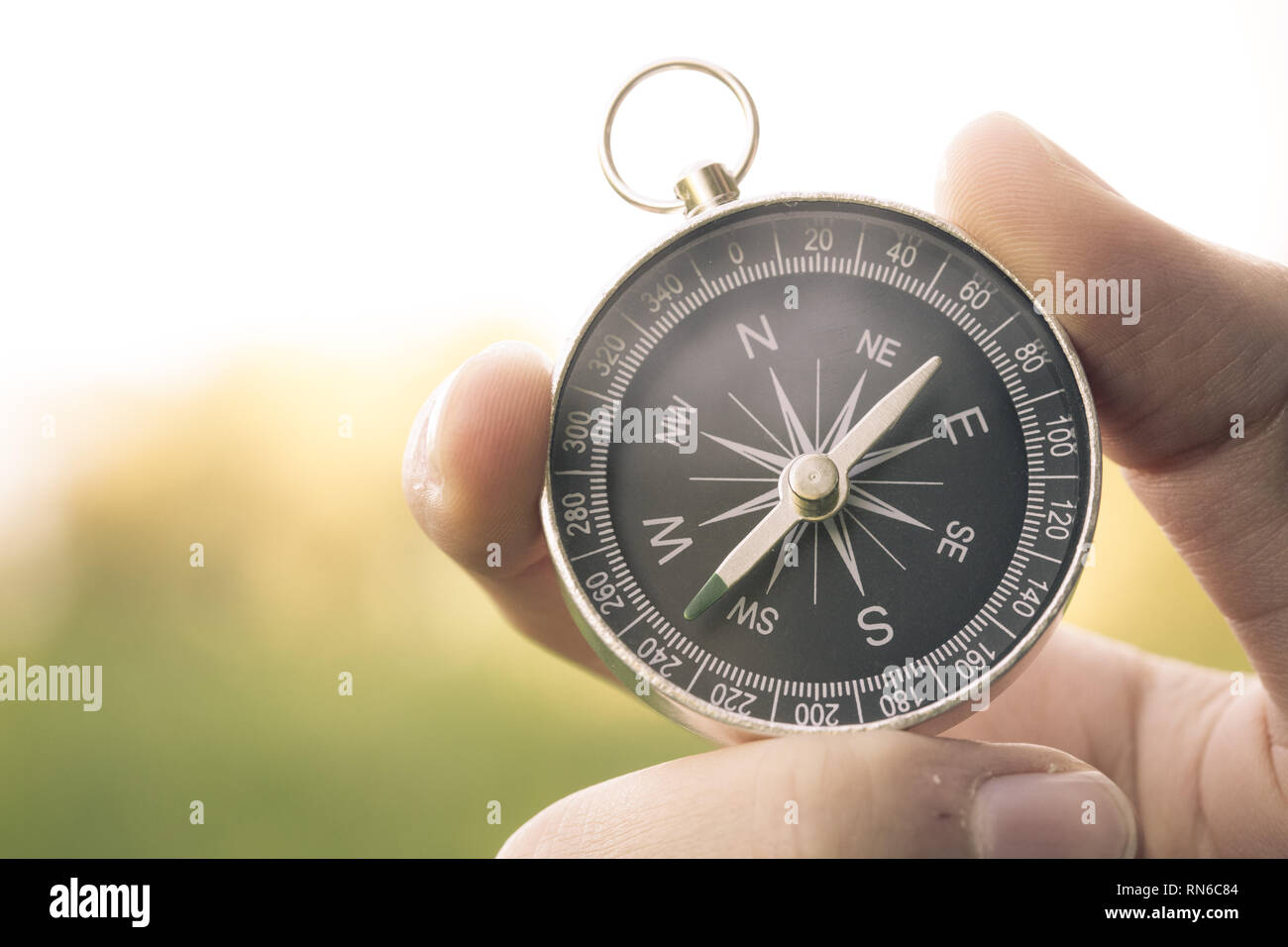 Young man on an adventure is holding a compass in his hand for finding ...