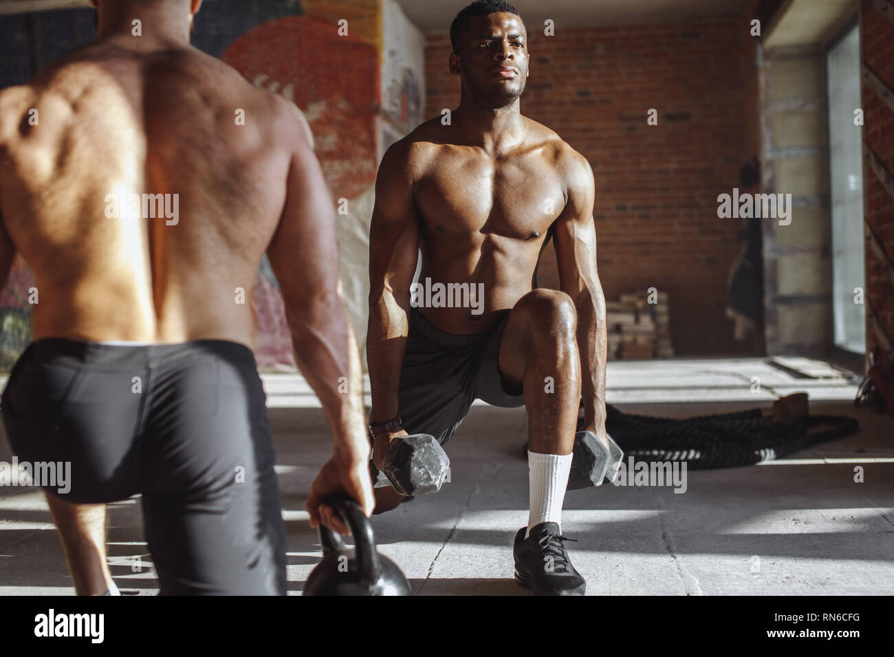 Powerful crossfit mixed race athletes in a deep lunge with a heavy ...