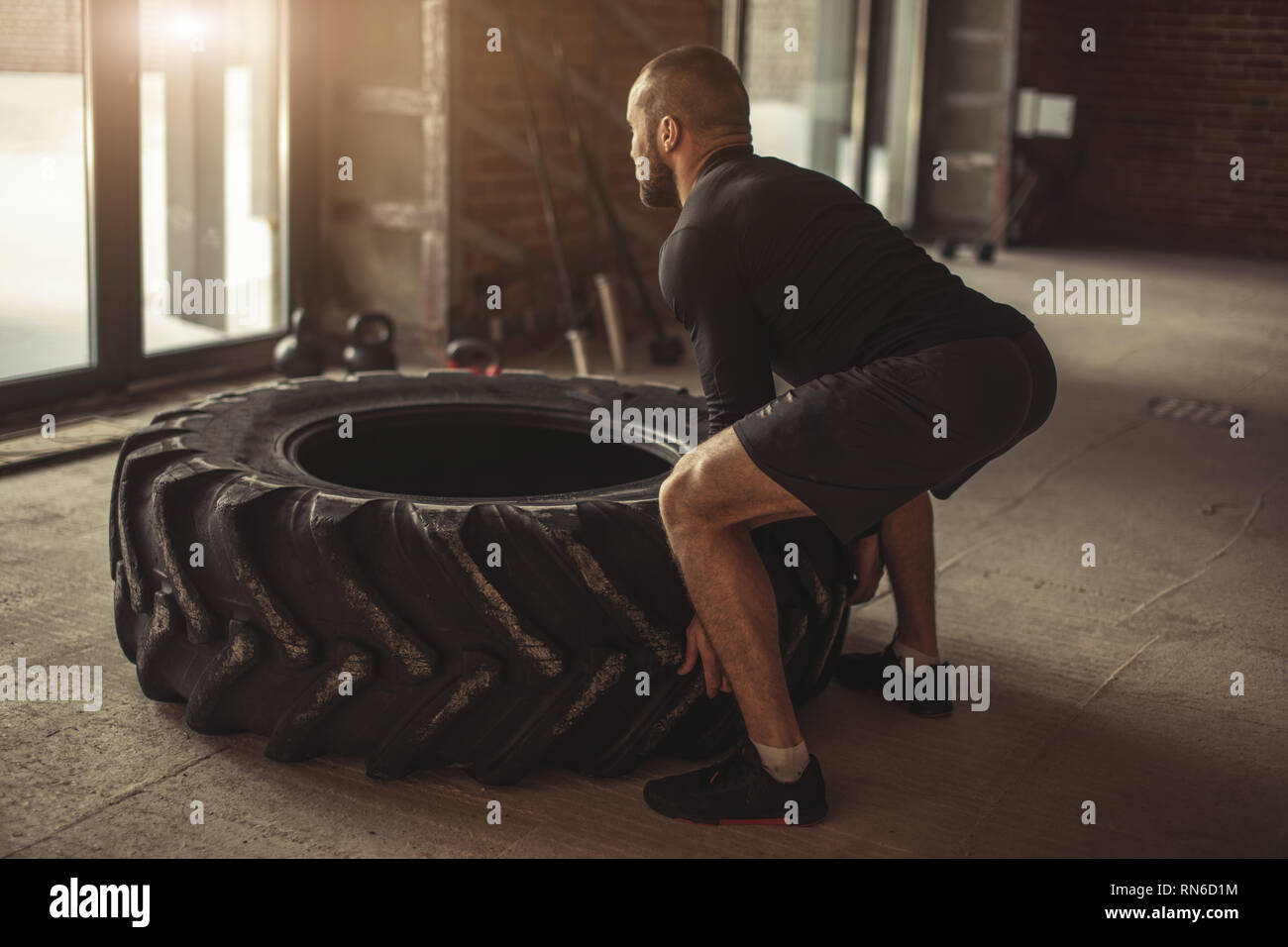 Young muscular bearded man using heavy tire in gym as improvised ...