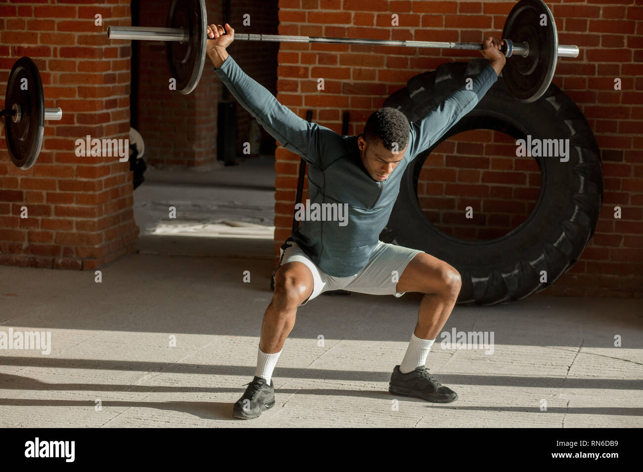 African male fitness model straining to lift heavy weights over his ...