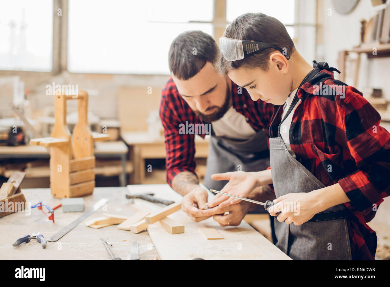 Little male helper working with his male teacher building wooden kit ...