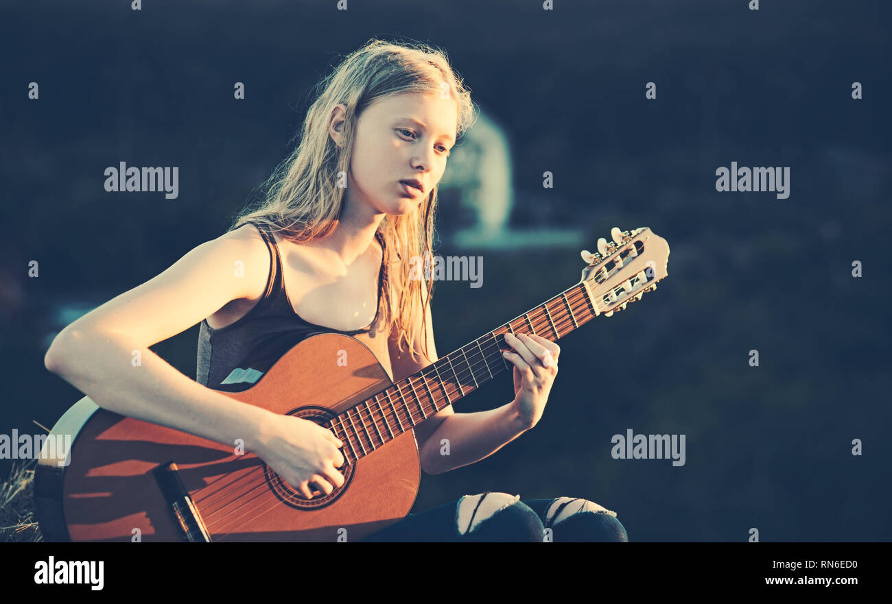 Nice caucasian young female playing guitar and singing sitting down ...