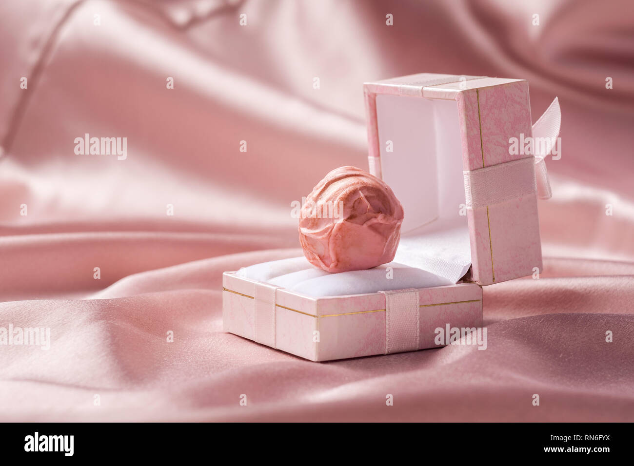 Candy cane in a festive box with a silk ribbon on a delicate pink satin ...