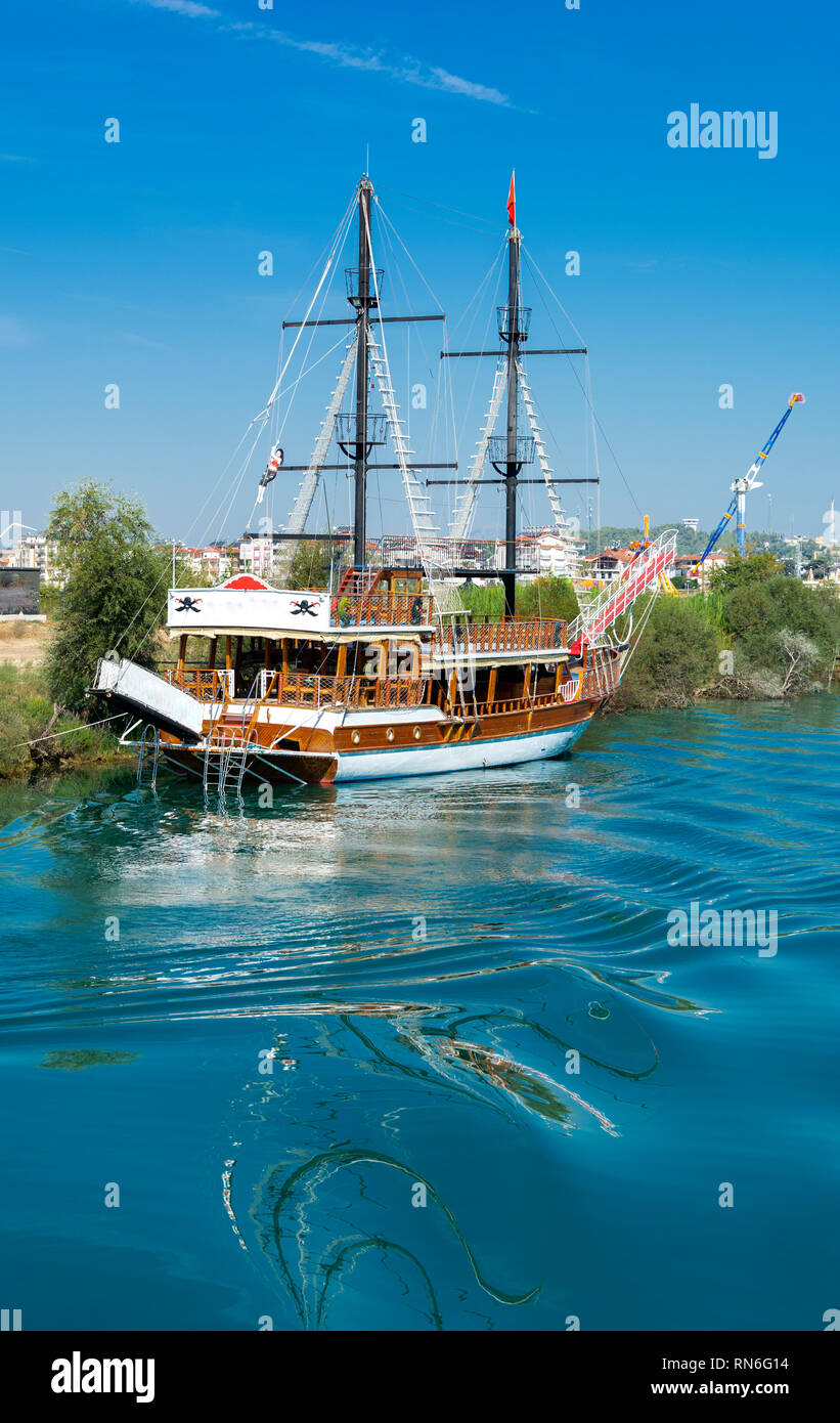 A small sailing ship with tourists passes along the coast against the ...