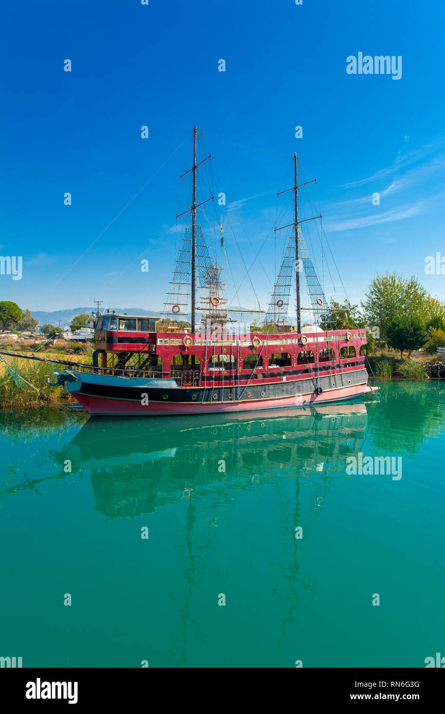 A small sailing ship with tourists passes along the coast against the ...