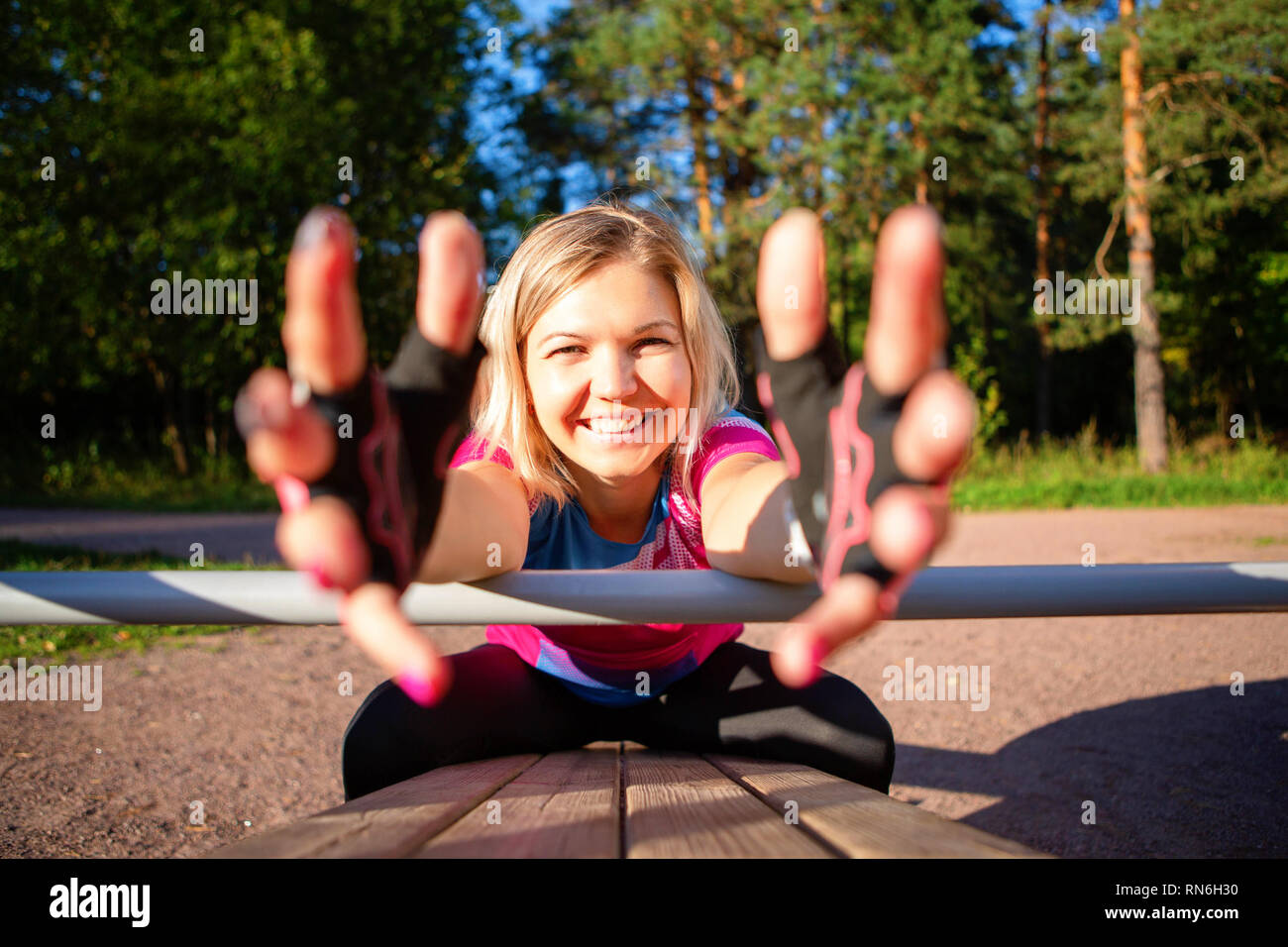 Athlete girl pulling hands forward is exercising at wooden bench in ...