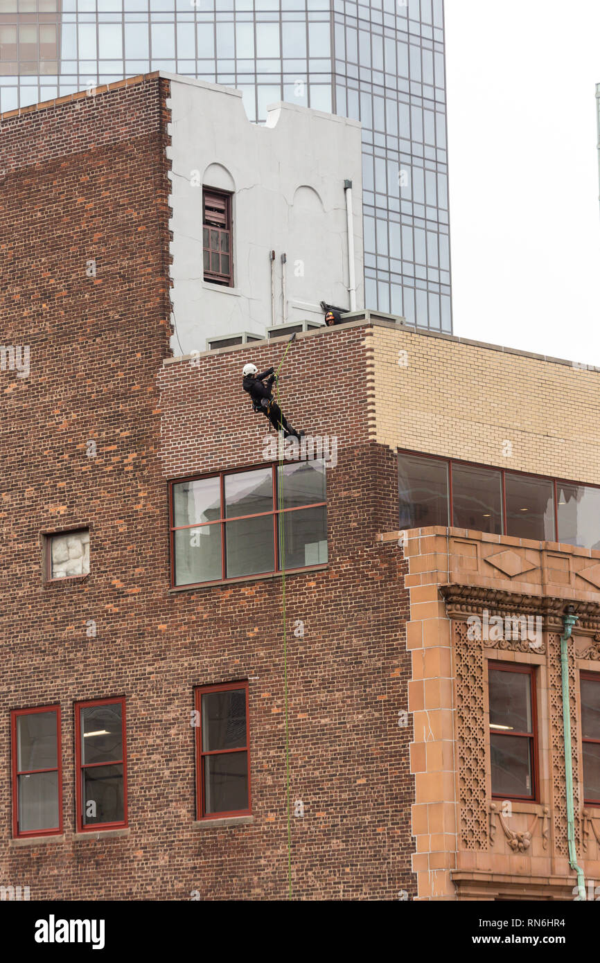 Industrial engineer rappelling down the side of a building on a ...