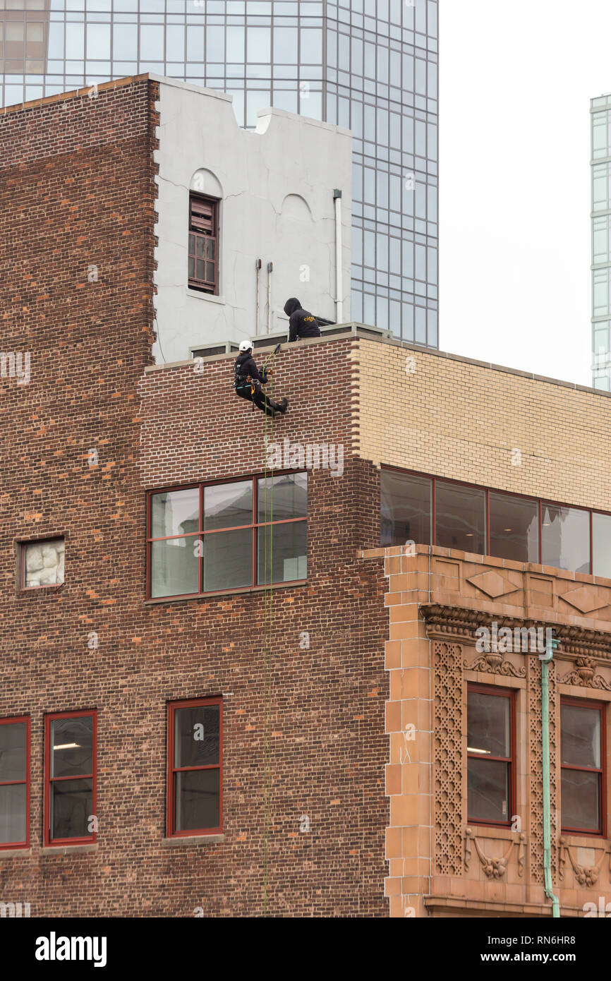 Industrial engineer rappelling down the side of a building on a ...