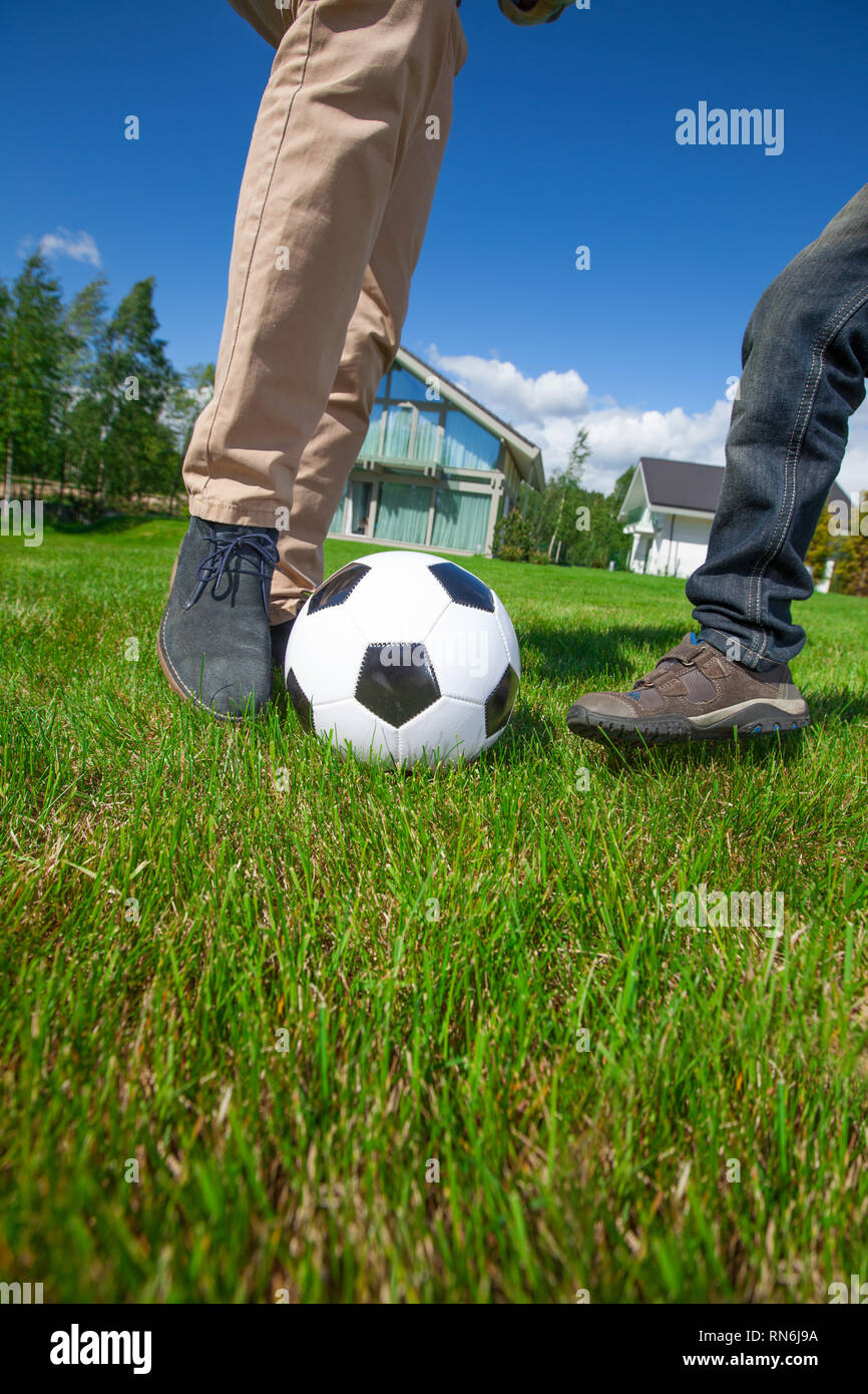 Cheerful father and son playing football on the backyard lawn near ...