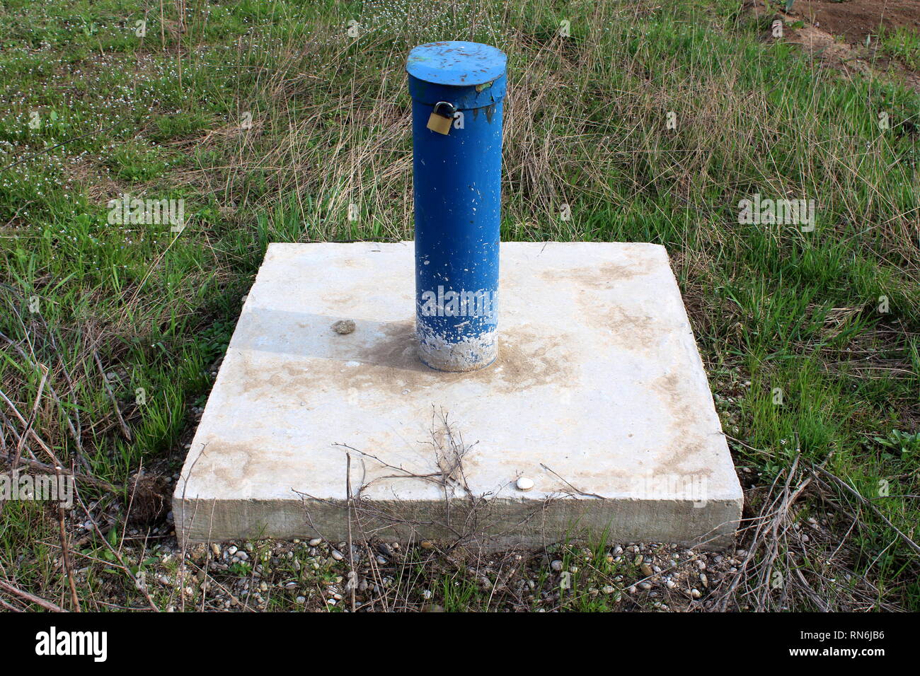 Industrial blue metal pipe with padlock locked cap on hard concrete ...
