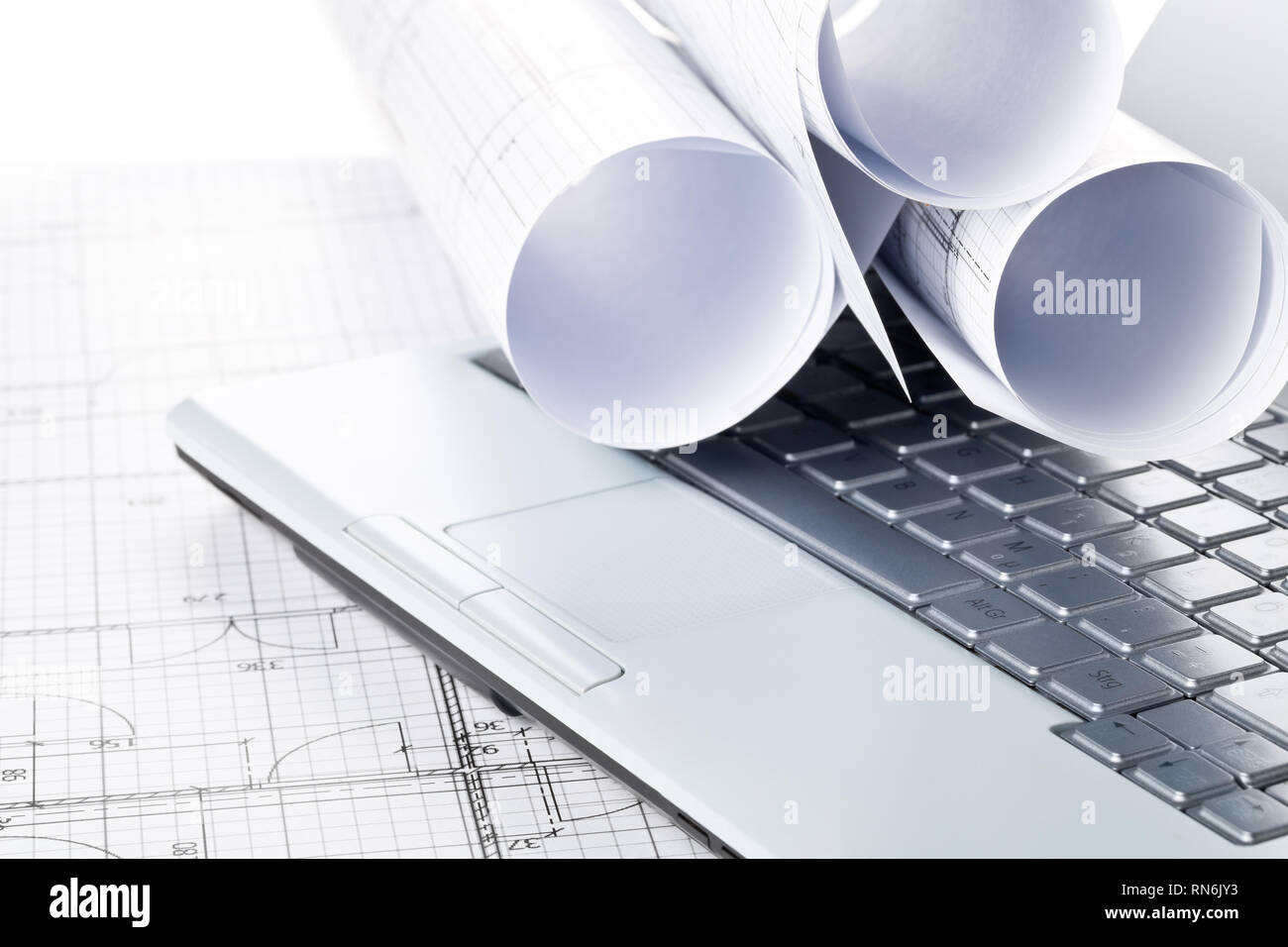 Rolls of architectural blueprint house building plans on laptop ...